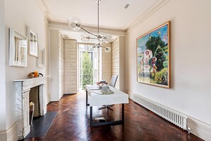 Uma sala de jantar com uma mesa branca, uma lareira e um quadro grande na parede.