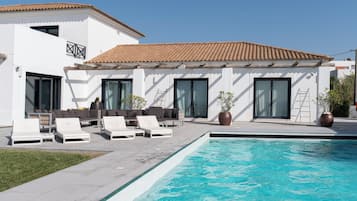 Uma casa moderna com piscina, área de estar externa e telhado telhado.