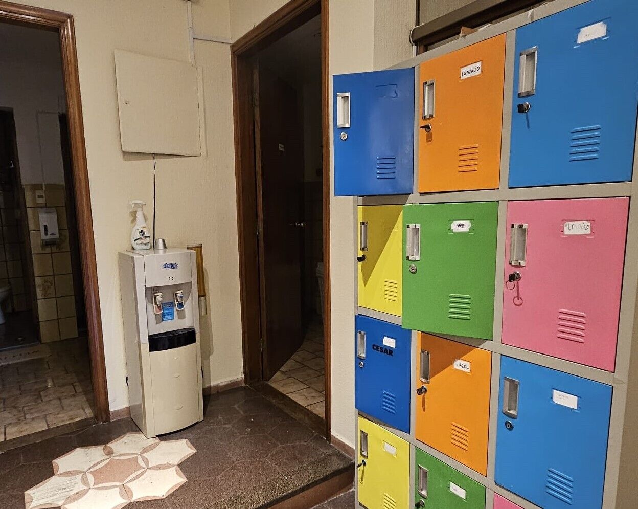 Um corredor com um bebedouro e uma fileira de armários coloridos.