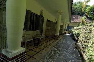 Uma área externa coberta com piso de azulejos, um banco e uma cadeira.