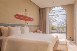 Quarto com uma cama grande, um mural de uma prancha de surf e vista para uma varanda externa com plantas.
