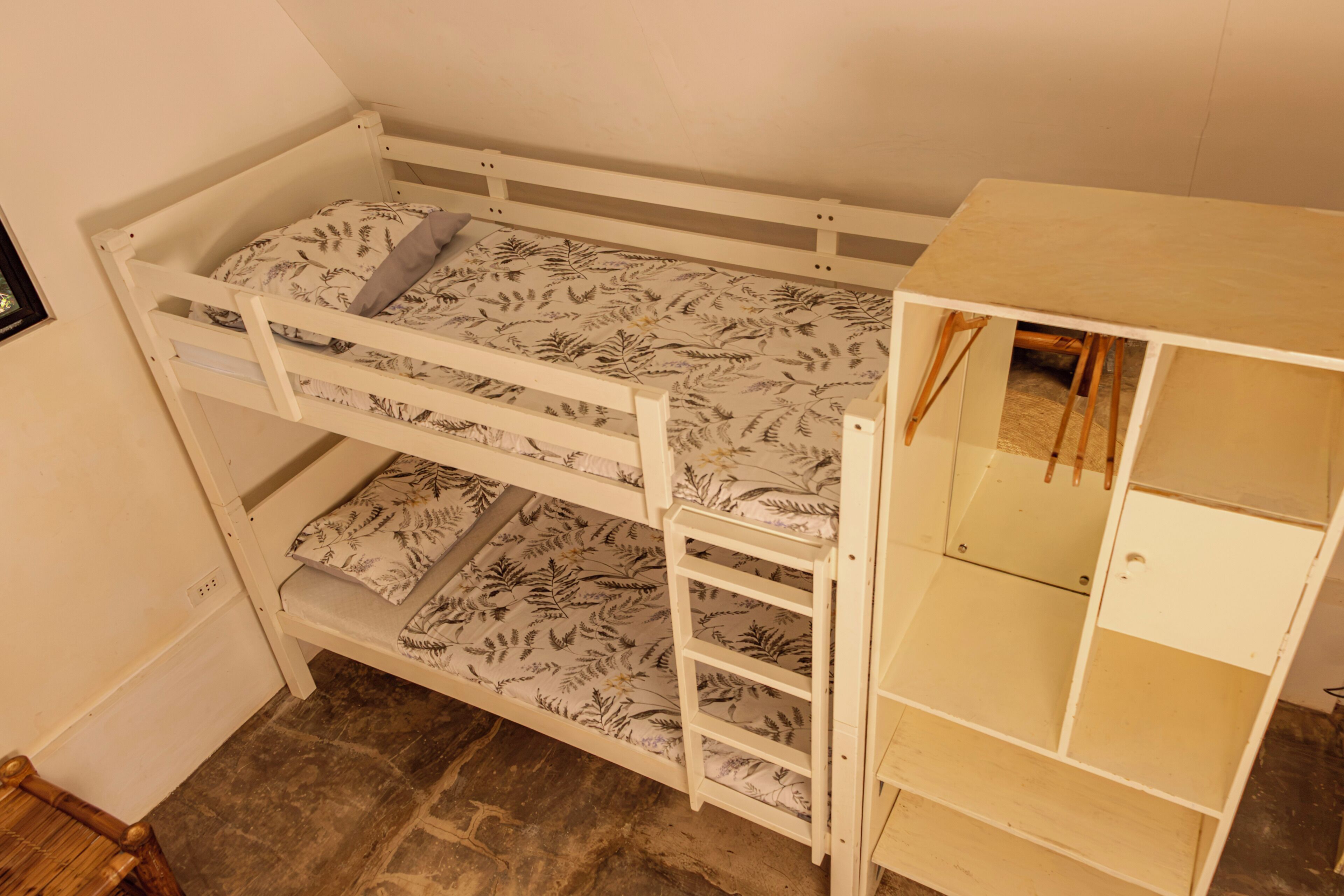 Uma cama beliche com uma cama inferior e um espaço de estudo pequeno com prateleiras.
