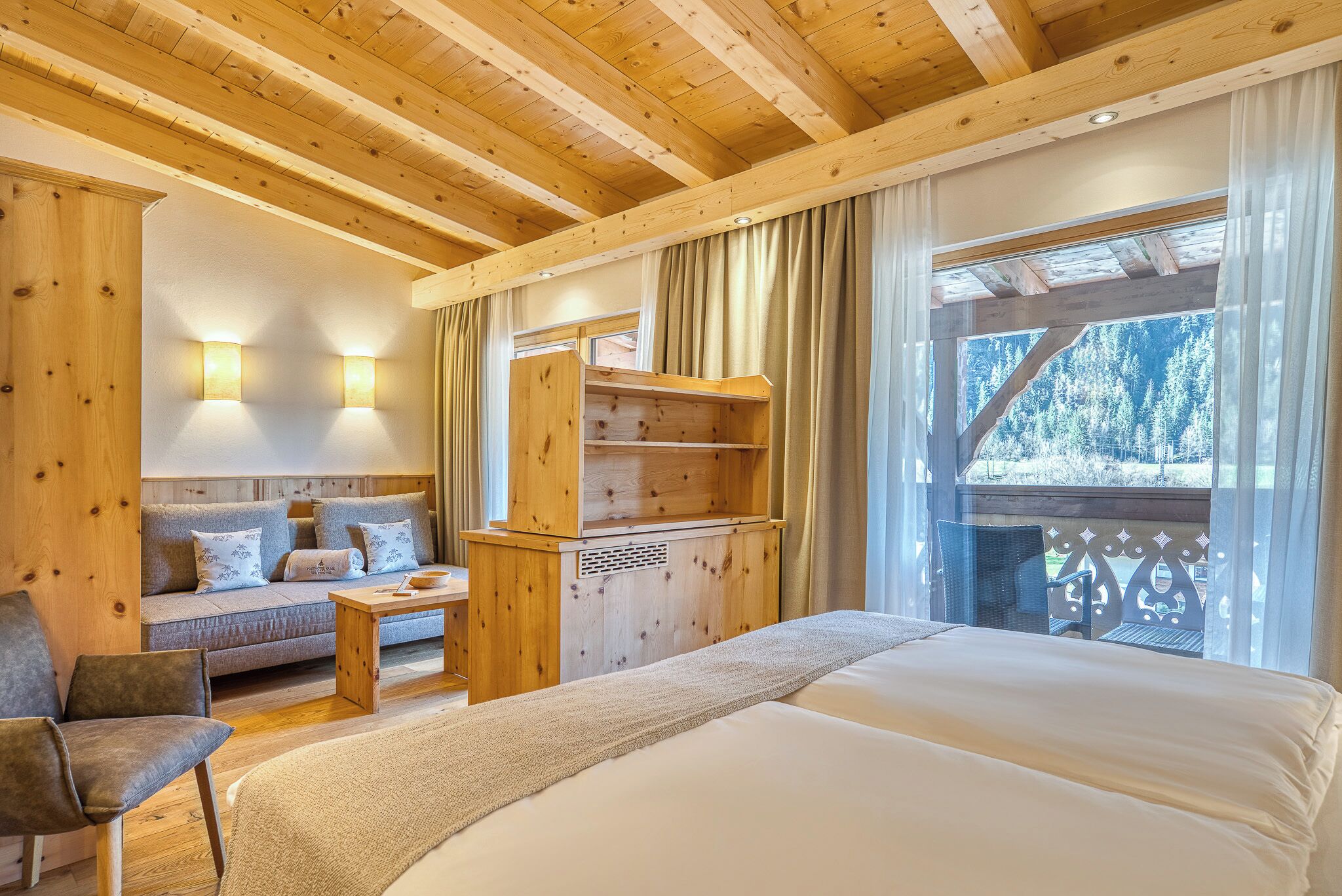 Interior de uma cabana de madeira com cama, sofá e uma pequena mesa.