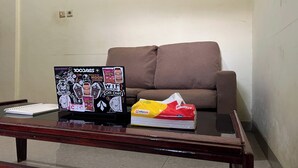 Uma sala de estar com um sofá marrom, uma mesa de centro de vidro e uma caixa de lenços.