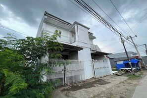 Um edifício de dois andares com fachada branca, portão e varanda visível.
