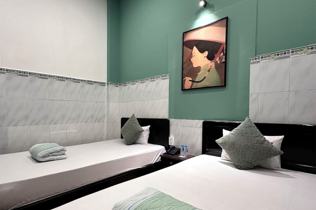 Quarto de hotel com duas camas, um quadro grande na parede e uma moldura decorativa no teto.