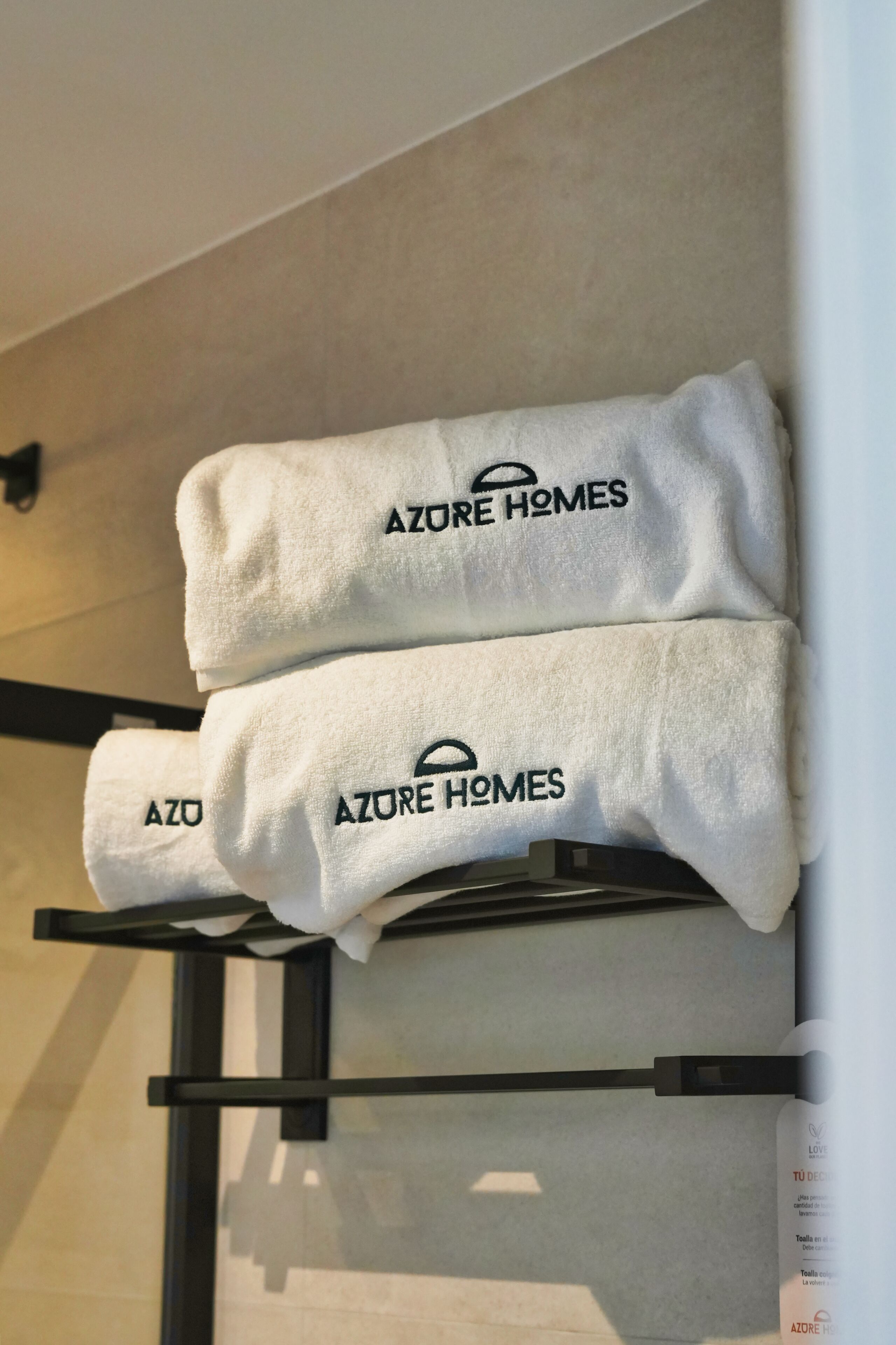 Um porta-toalhas com toalhas dobradas, cada uma delas com a etiqueta 'AZURE HOMES'.