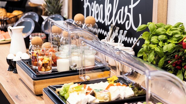 Buffet com diversas opções de comida, incluindo frutas, queijos e carnes.