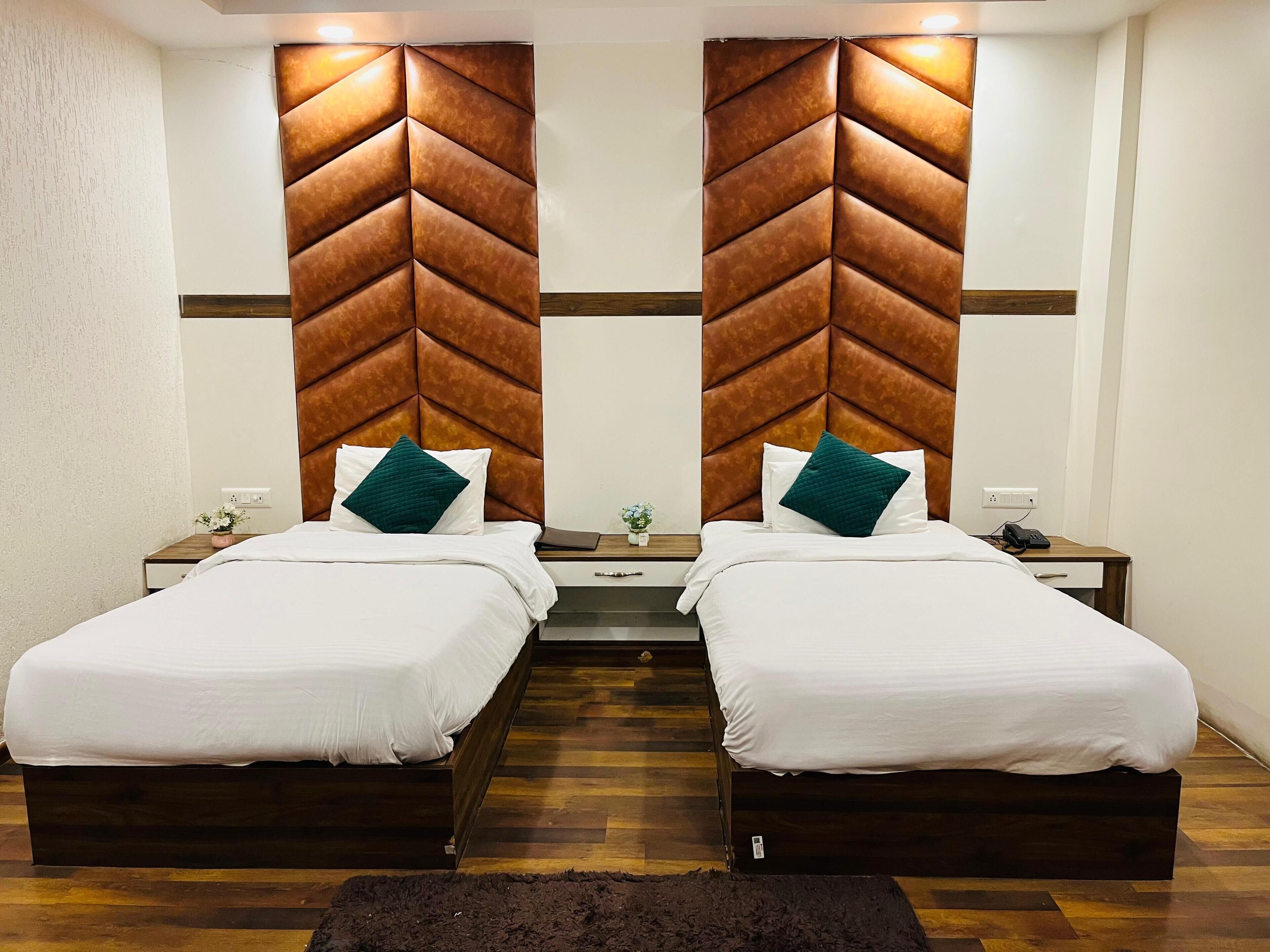 Quarto de hotel com duas camas, piso de madeira e design de parede com espelhos.