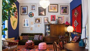 Uma sala de estar acolhedora com um sofá verde, um armário de madeira e um tapete vermelho estampado.