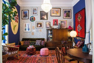 Uma sala de estar acolhedora com um sofá verde, um armário de madeira e um tapete vermelho estampado.
