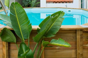 Uma área de madeira à beira da piscina, com uma piscina e grandes folhas verdes.