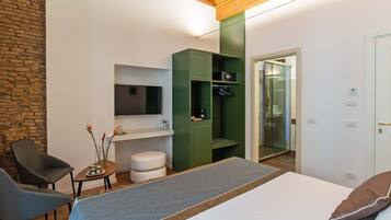 Quarto de hotel moderno com cama, área de estar, TV, guarda-roupa verde e chuveiro.