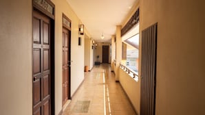 Um corredor com portas de madeira, placas numeradas e chão de azulejos.