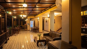 Um restaurante acolhedor com móveis de madeira, piso ladrilhado e um ventilador.