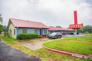 Um motel com telhado vermelho e uma placa que diz 'Motel'.