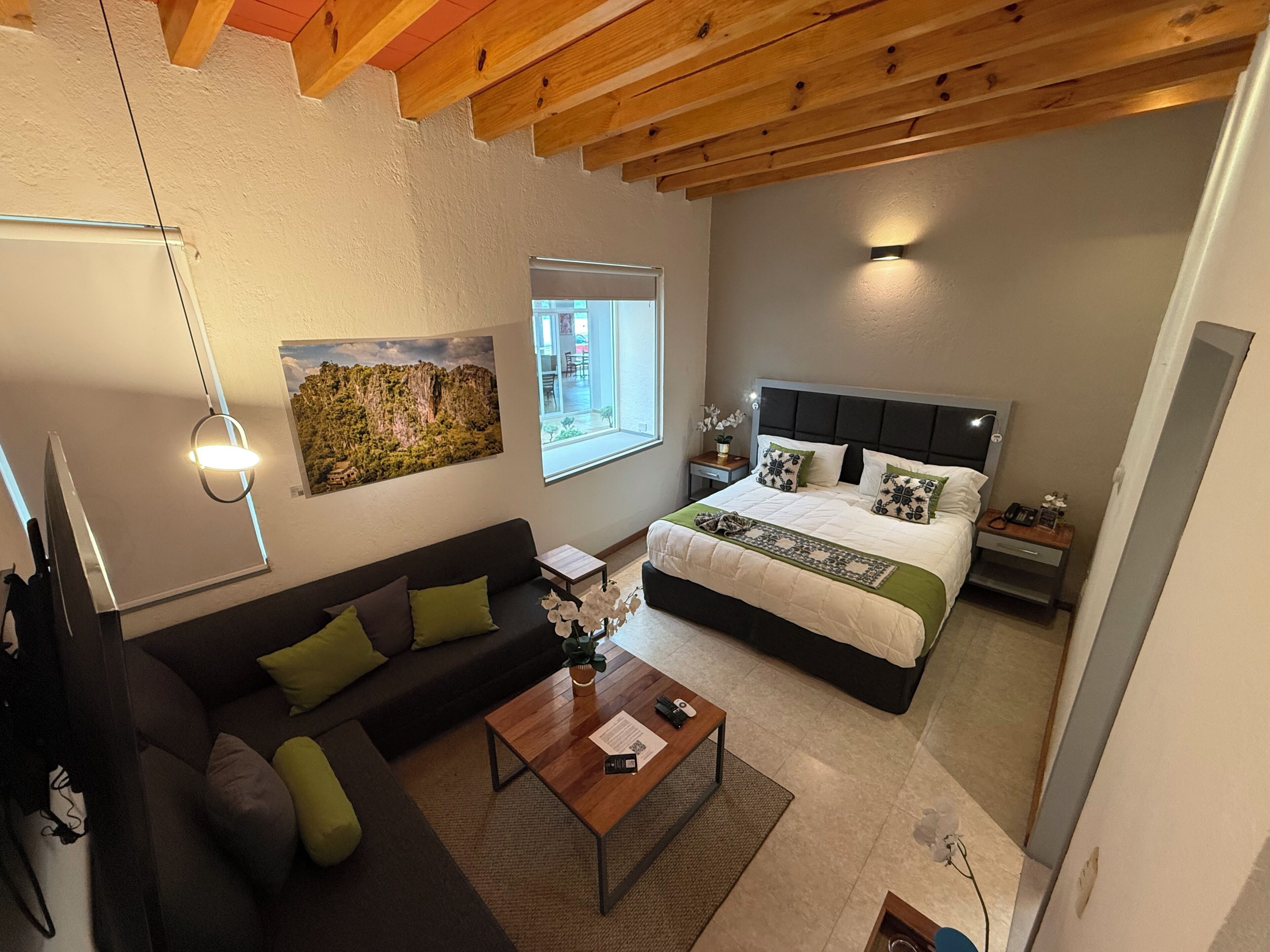 Um quarto moderno com uma cama grande, um sofá, uma mesa de centro e um quadro na parede.