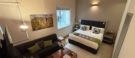 Um quarto moderno com uma cama grande, um sofá, uma mesa de centro e um quadro na parede.