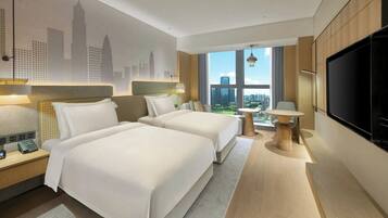 Quarto de hotel moderno com duas camas, uma televisão grande e vista para a cidade.