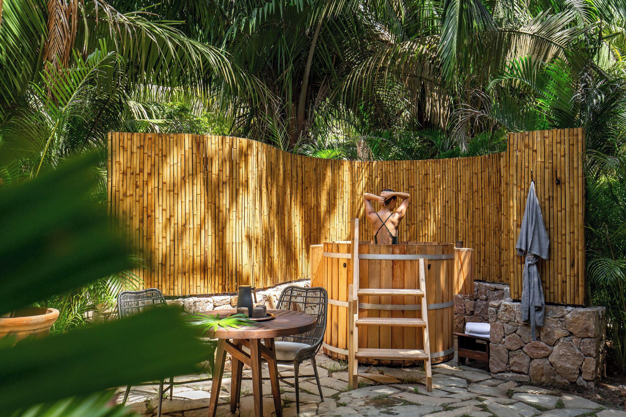 Cercas de bambu, área de estar ao ar livre, uma escada de madeira e um banco de pedra.