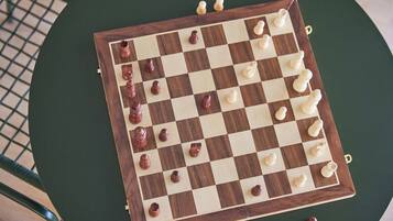 Um tabuleiro de xadrez com peças sobre uma mesa verde escura.
