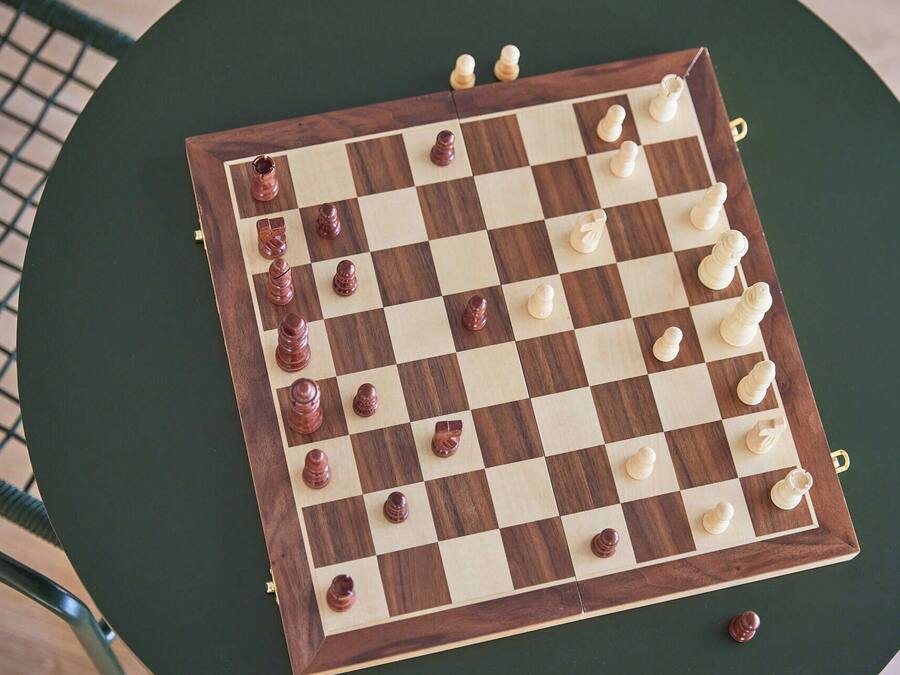 Um tabuleiro de xadrez com peças sobre uma mesa verde escura.
