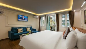 Quarto de hotel com cama, sofá azul, televisão e vista para a varanda.