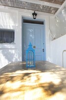 Uma mesa de madeira com um candeeiro azul em frente a uma porta branca.