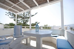 Área de estar coberta ao ar livre, com mesa e cadeiras, voltada para uma vista panorâmica.
