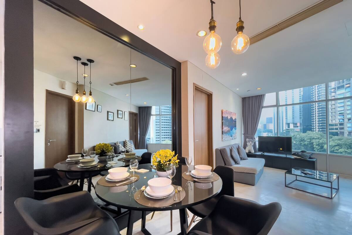 Uma sala de jantar moderna com uma mesa redonda, cadeiras pretas e um espelho grande.
