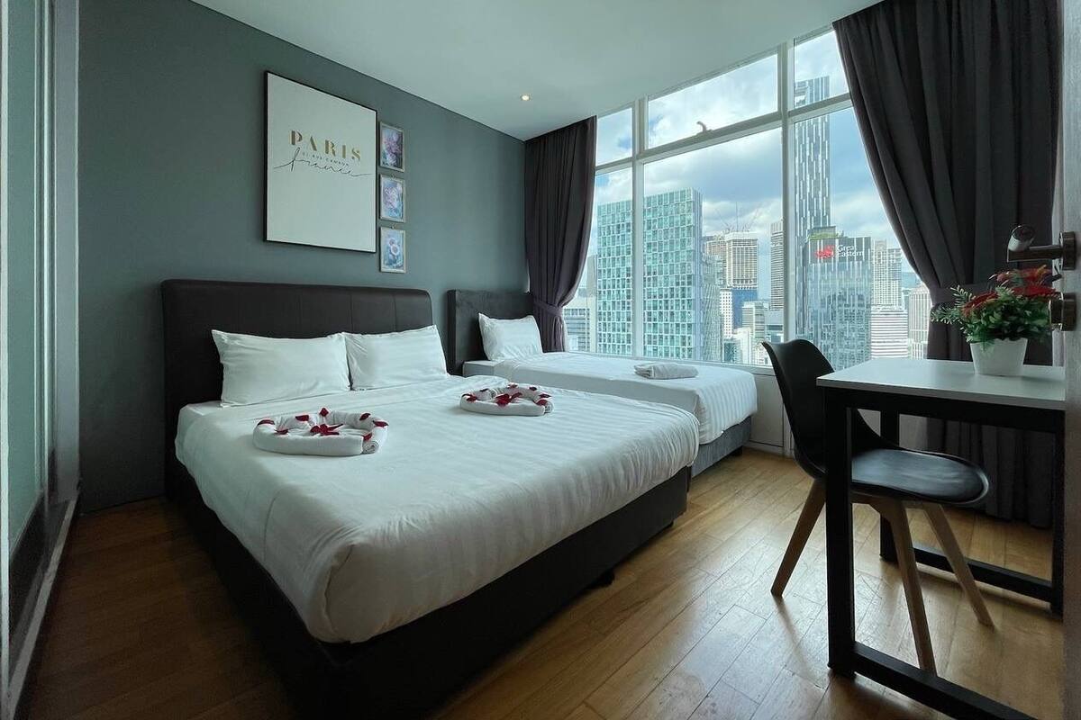 Quarto de hotel com duas camas, uma mesa de jantar e vista para a cidade.