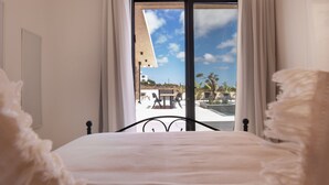 Quarto com uma grande janela, uma cama e vista para um pátio externo.