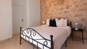 Quarto com uma cama, mesa de cabeceira e parede de pedra.