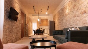 Uma sala de estar moderna com parede de pedra, televisão de tela plana, área de jantar com mesa e cadeiras, e um sofá.