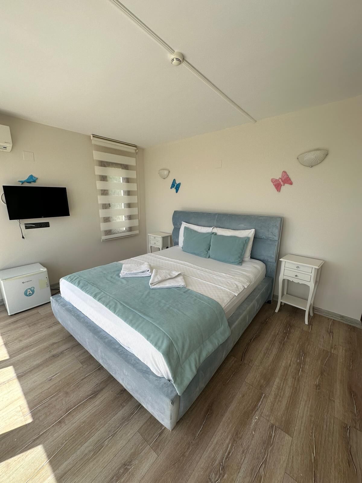 Quarto com cama, televisão, aquecedor e janela com persianas.