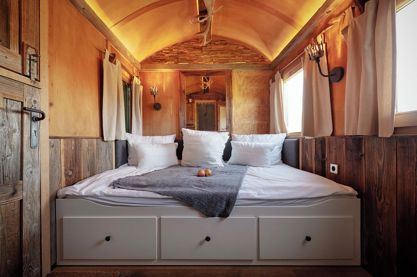 Um quarto aconchegante, com decoração em madeira, uma cama, travesseiros e um cobertor.