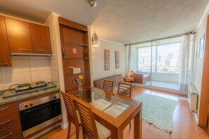 Cozinha moderna com área de jantar, uma grande janela com vista para a cidade e um espaço de estar aconchegante.