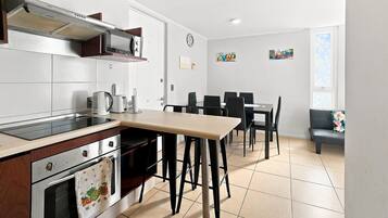 Cozinha moderna com área de jantar, equipada com forno embutido, cafeteira e mesa com cadeiras.