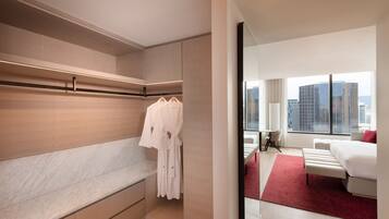 Quarto de hotel moderno com uma cama grande, área de estar e vista para a cidade.