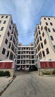 Um hotel com vários andares, pátio central e varandas em cada andar, sob um céu claro.