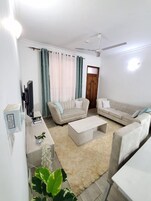 Uma sala de estar com dois sofás, uma mesa de centro, uma televisão e um ventilador de teto.