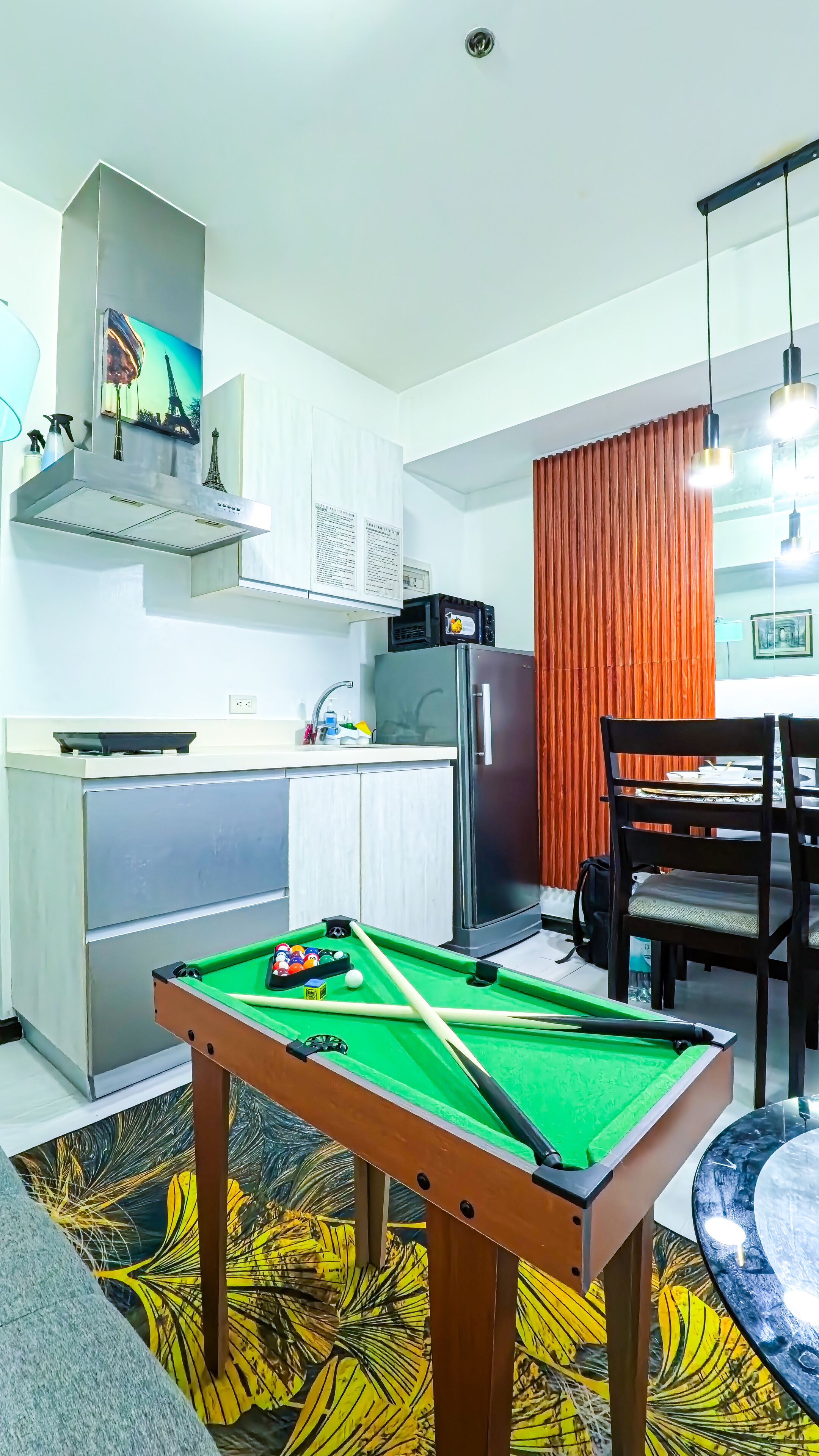 Cozinha moderna com mesa de bilhar, frigorífico e área de refeições com mesa e cadeiras.