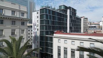Um edifício moderno com fachada de vidro, cercado por palmeiras e outros edifícios.