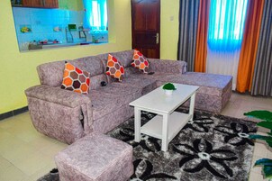 Uma sala de estar com sofá, banqueta e mesa de centro.