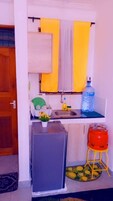 Uma cozinha compacta com pia, bebedouro e uma geladeira pequena.