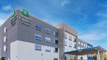 Edifício do Holiday Inn Express & Suites com design moderno, apresentando uma entrada coberta e estacionamento.