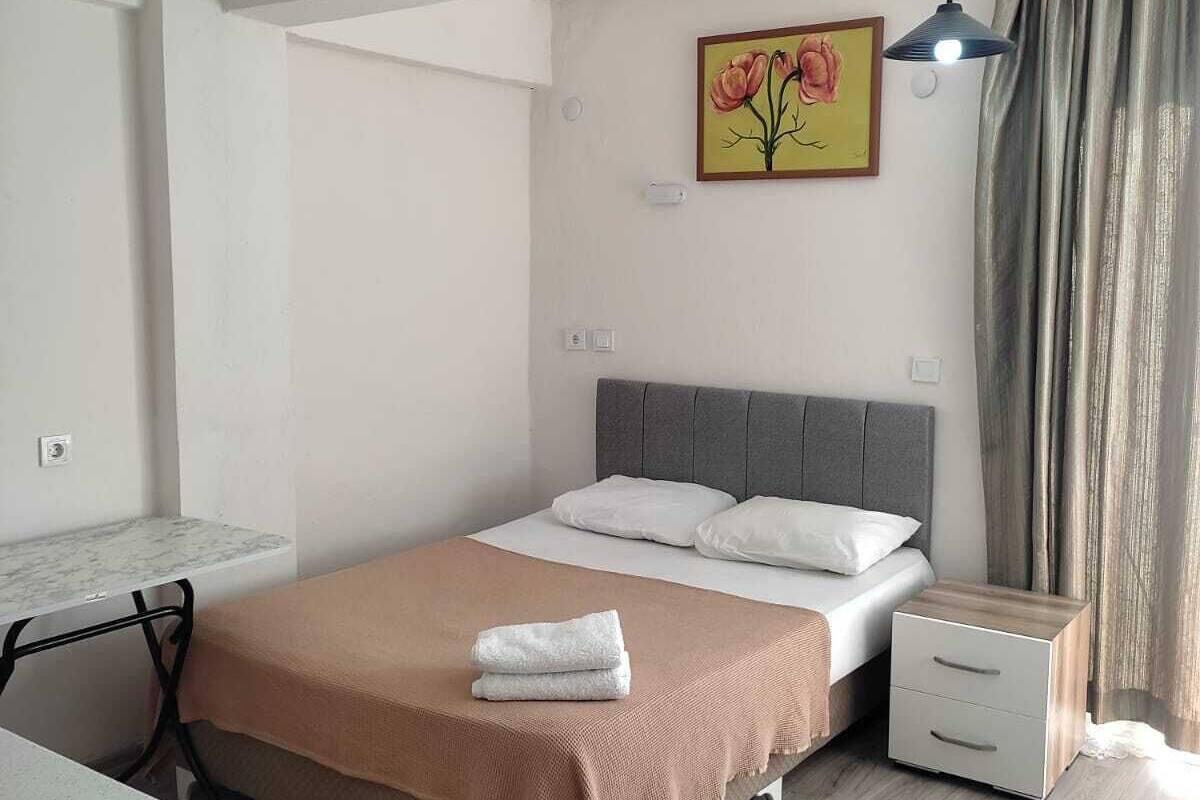 Quarto moderno com cama, mesas de cabeceira, escrivaninha e um quadro na parede.
