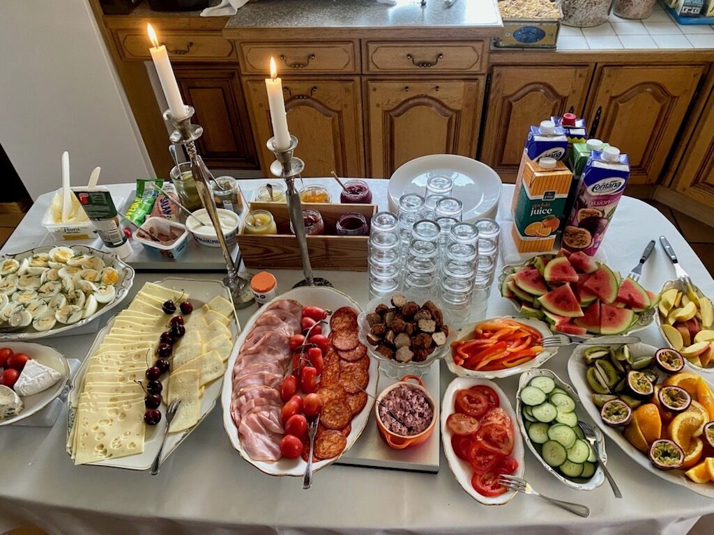 Uma mesa com diversos alimentos e acompanhamentos, incluindo queijos, carnes, frutas e legumes.