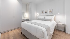 Quarto com cama, mesa de cabeceira, ventoinha no teto e guarda-roupa.