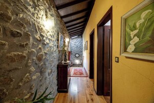 Um corredor com paredes de pedra, piso de madeira e um tapete vermelho que leva a uma porta.